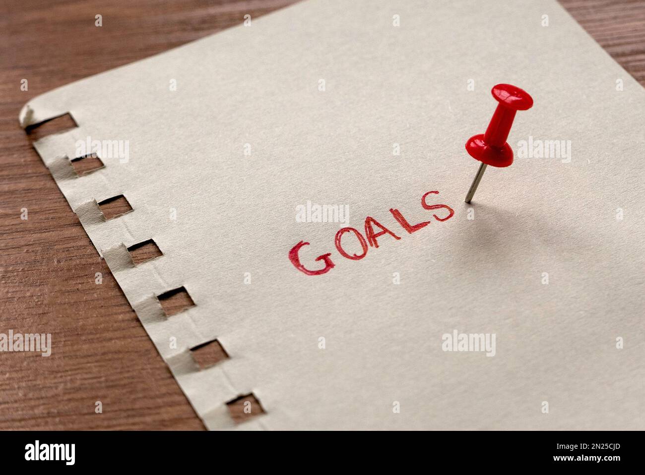 A paper written with GOALS with a red push pin beside Stock Photo - Alamy