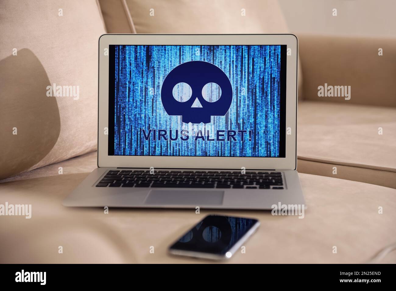 Smartphone and laptop with warning about virus attack on beige sofa ...