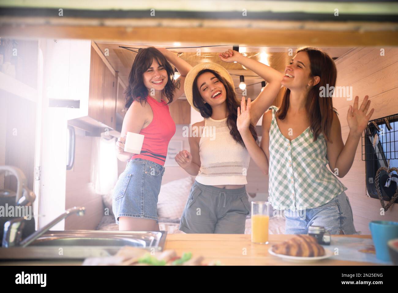 Happy young women dancing in trailer. Camping vacation Stock Photo - Alamy