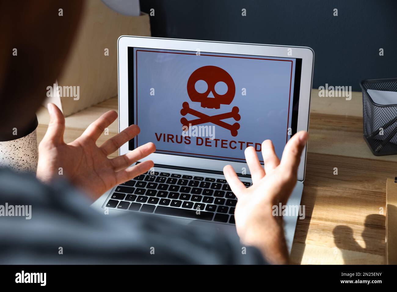 Man in front of laptop with warning about virus attack at workplace ...