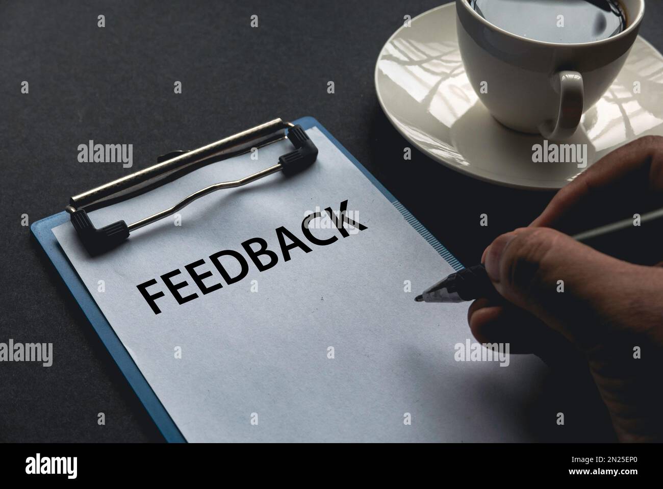 A man writing on a clipboard with paper written with Feedback Stock ...