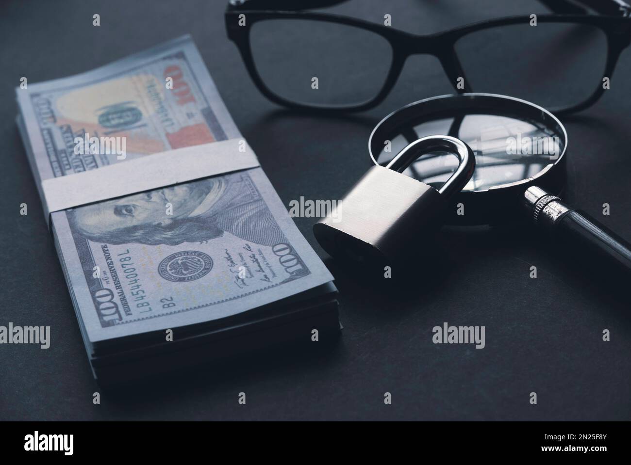 A money, magnifying glass, glasses and padlock on a black background ...