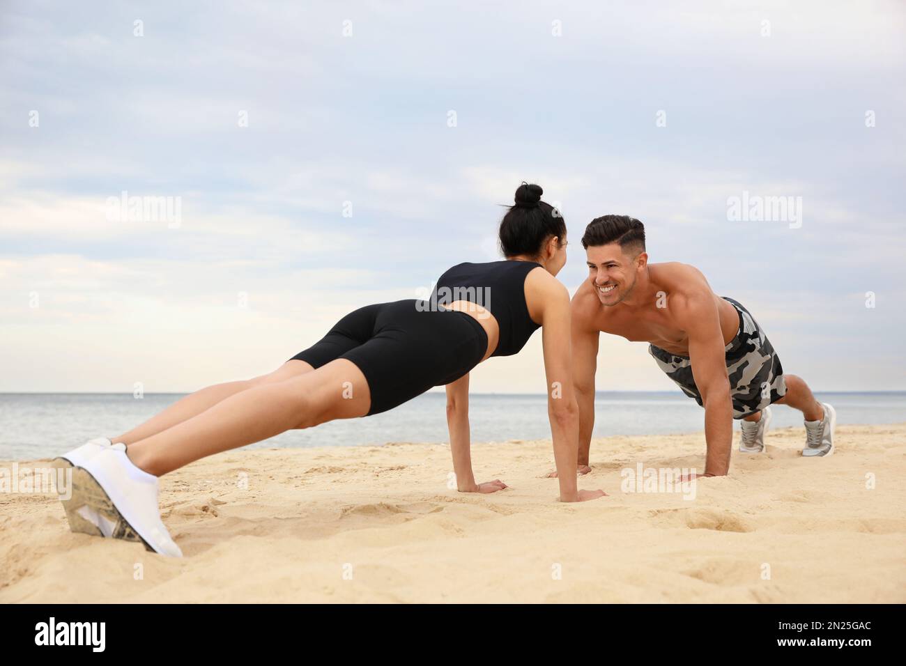 Couple doing exercise together on beach. Body training Stock Photo - Alamy