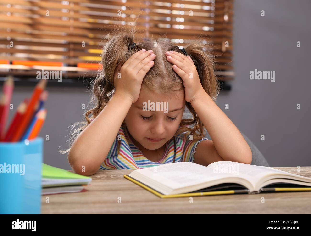 Tired little girl at table. Doing homework Stock Photo - Alamy