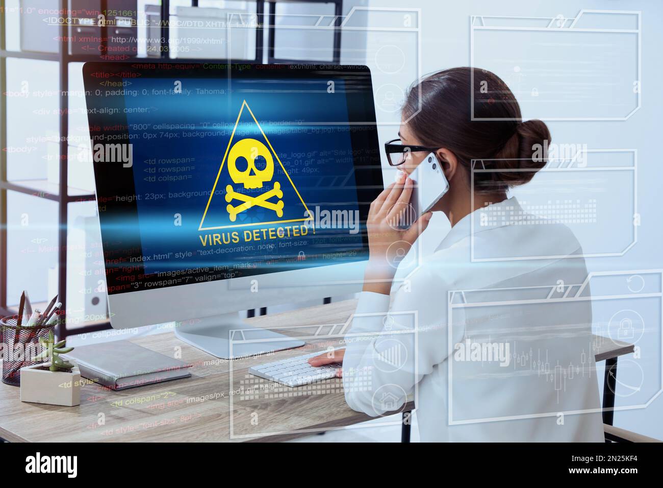 Office worker in front of computer with warning about virus attack on ...