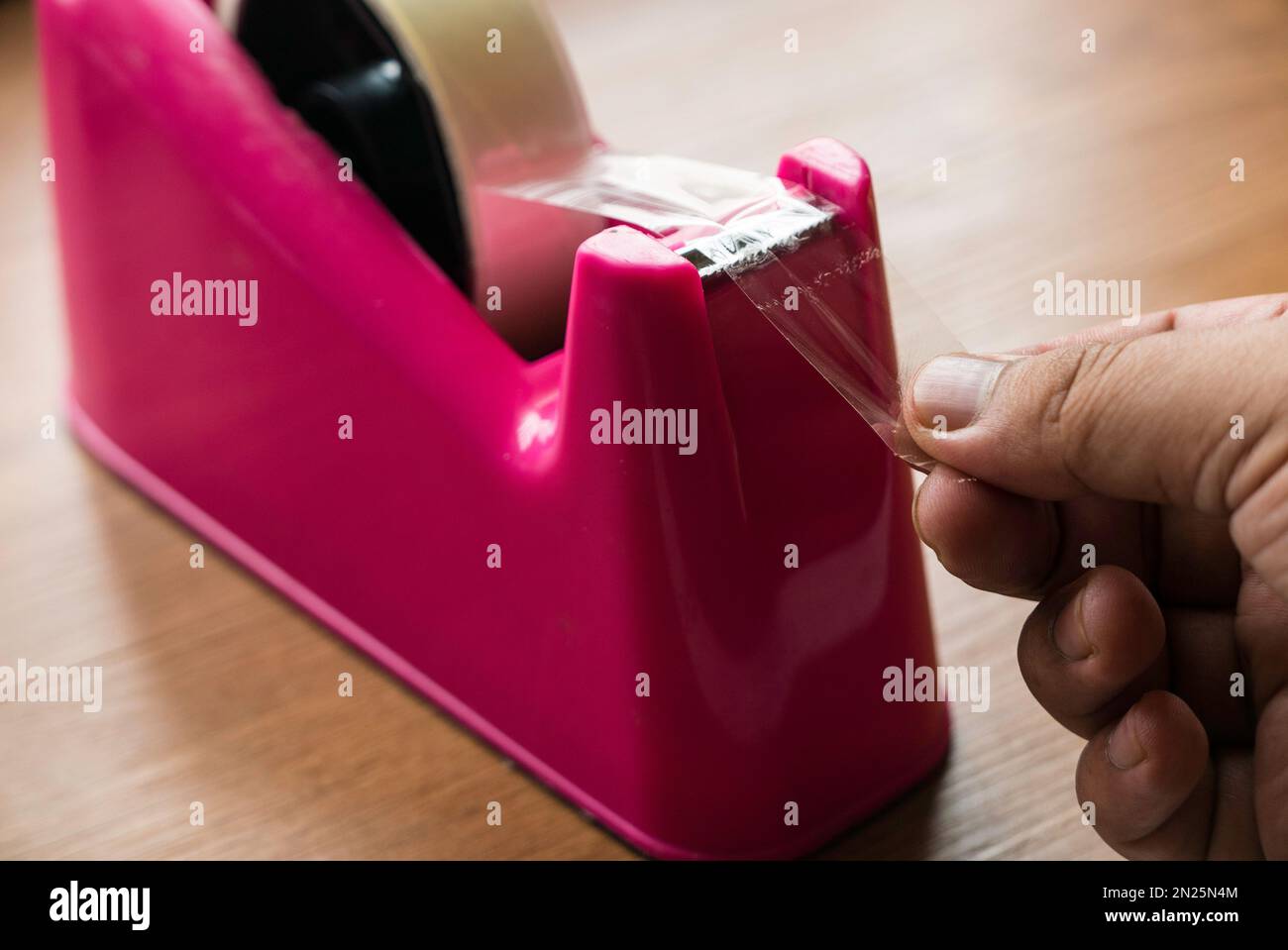 Selective focus of hand pulling a transparent tape from a tape ...