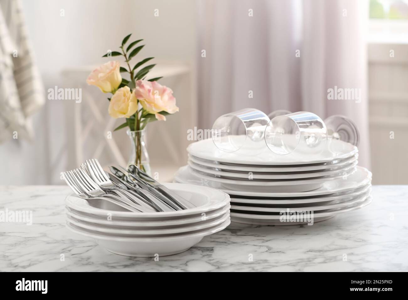 Set with clean dishes and vase of flowers on white marble table Stock ...