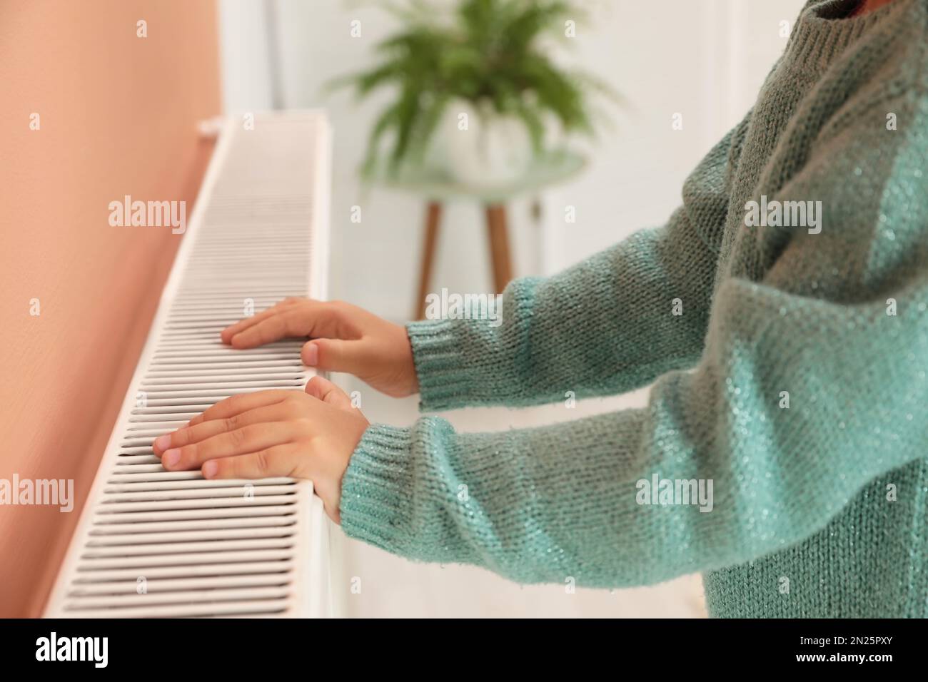 Child warming hands on heating radiator indoors, closeup Stock Photo ...