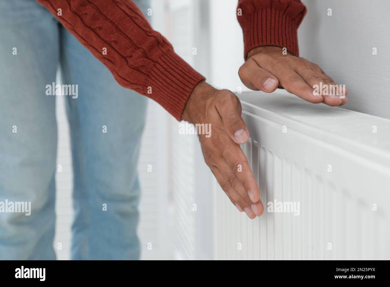 Man warming hands on heating radiator near white wall, closeup Stock ...