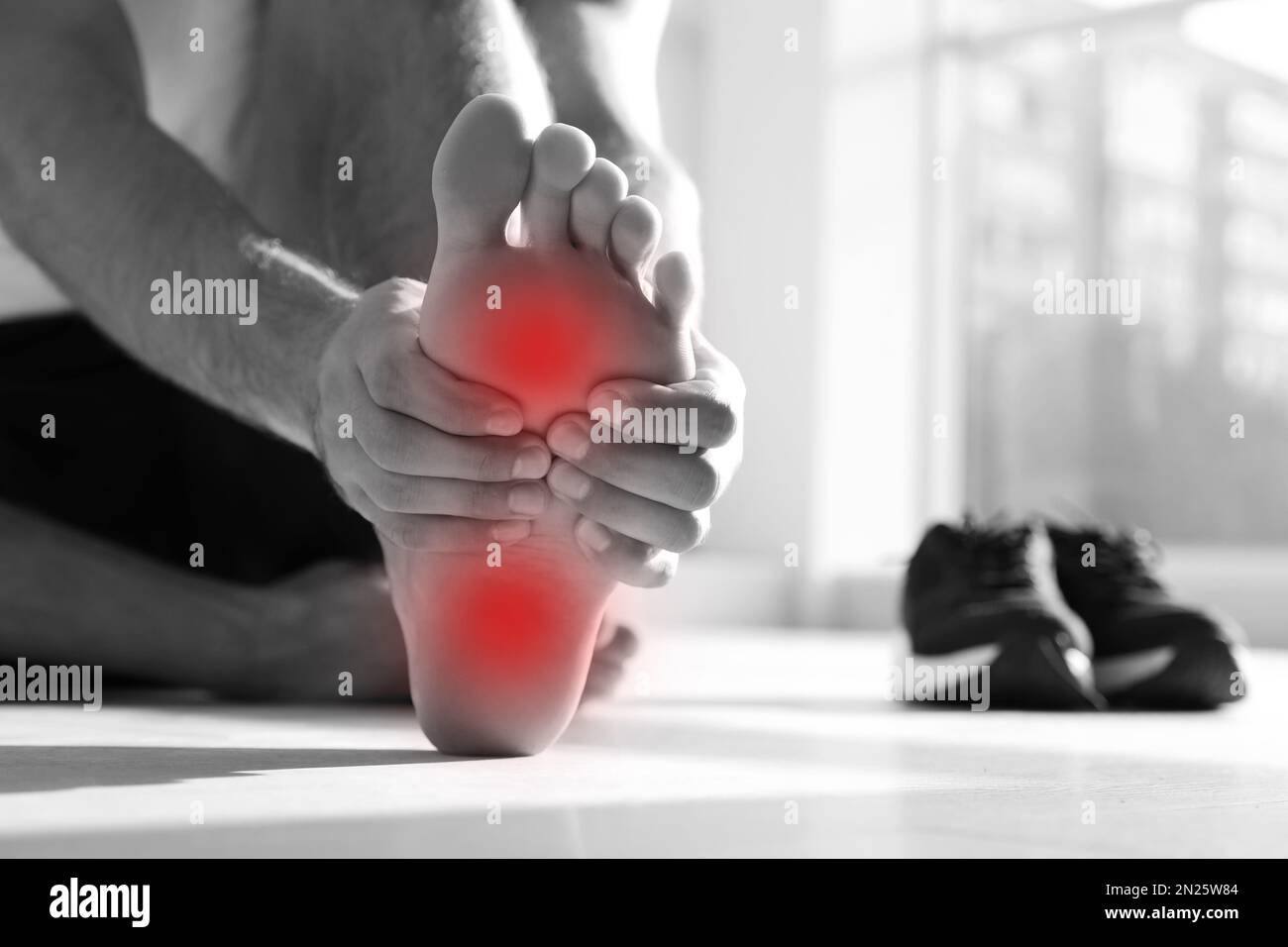 Man suffering from foot pain on floor indoors, closeup Stock Photo - Alamy