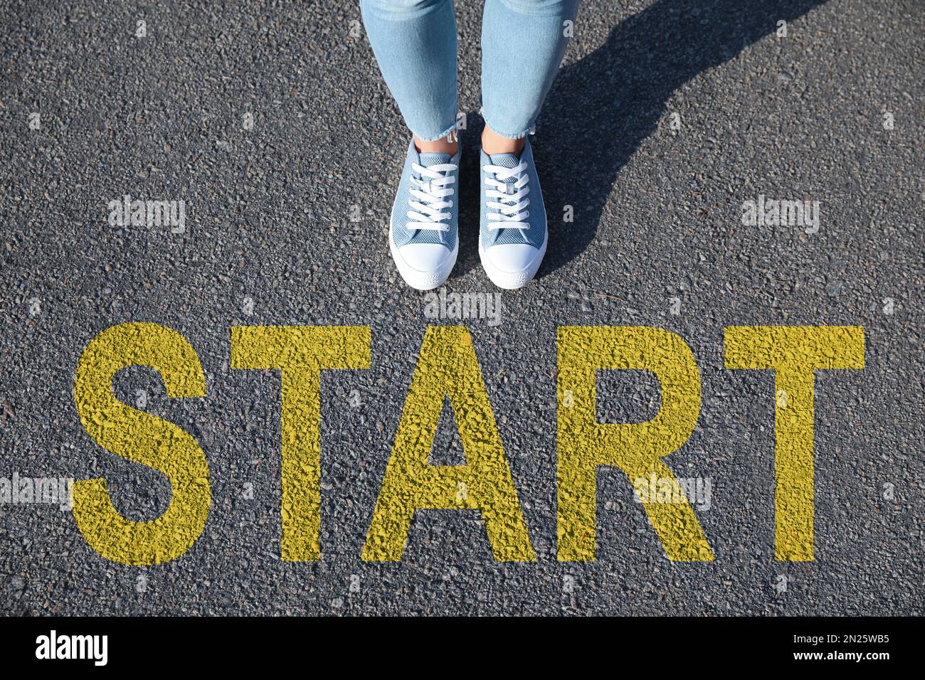 Word Start on asphalt in front of woman, above view Stock Photo - Alamy