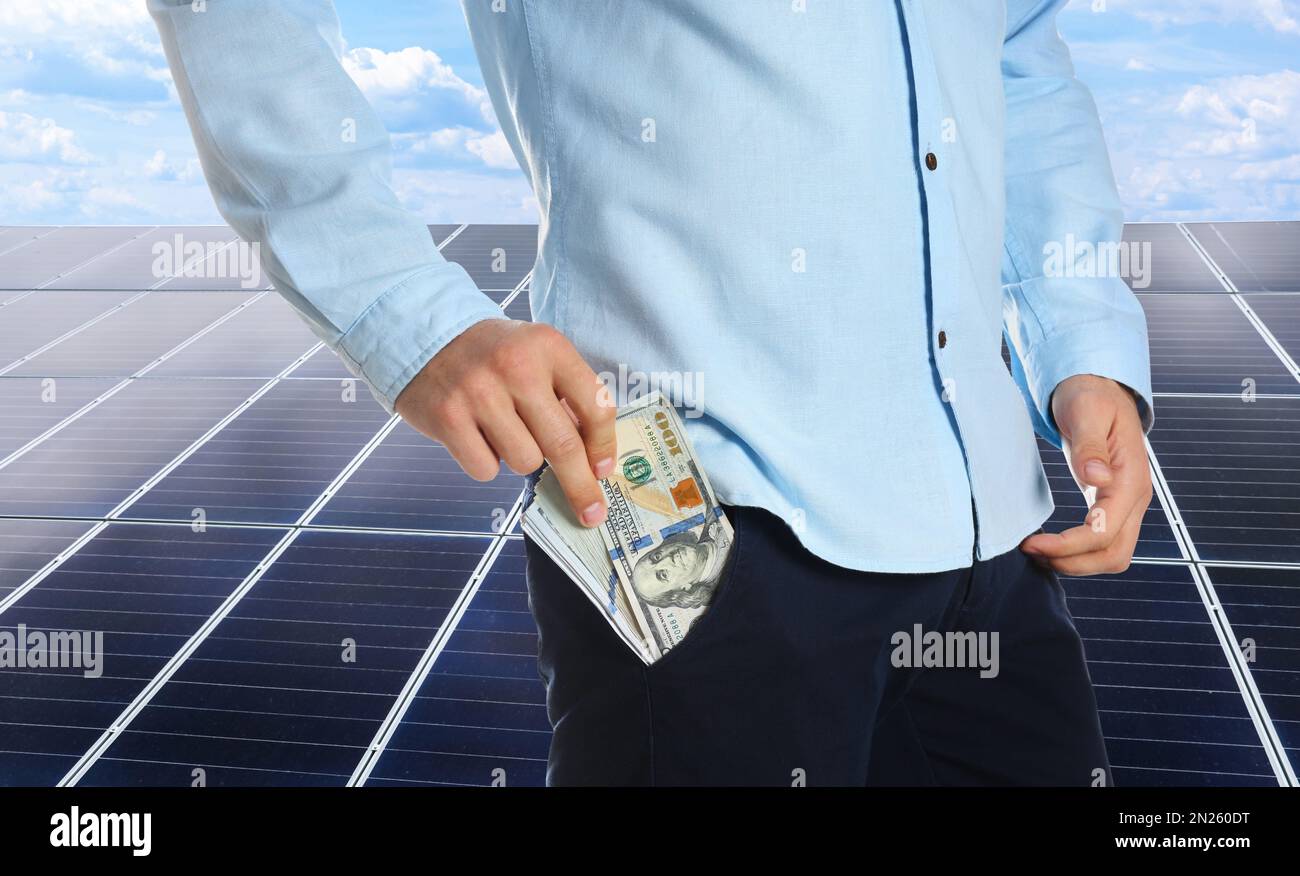 Man with money and installed solar panels on background, closeup ...