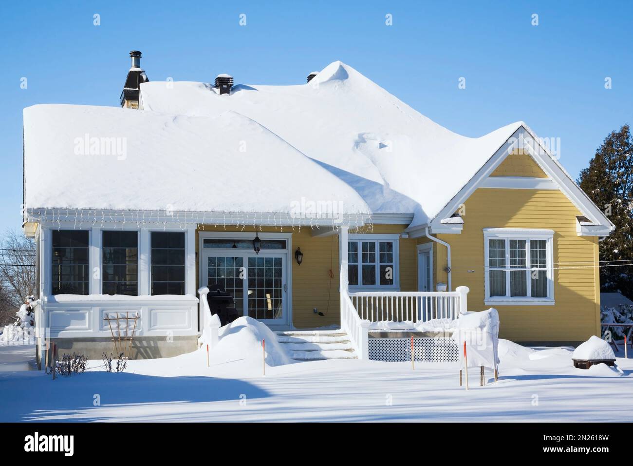 Rear of yellow with white trim country cottage style house in winter ...