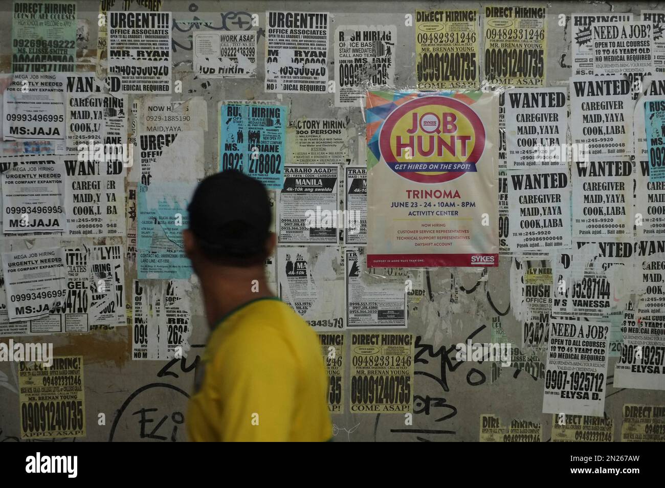 A Filipino looks at posters about job opportunities on a wall in ...