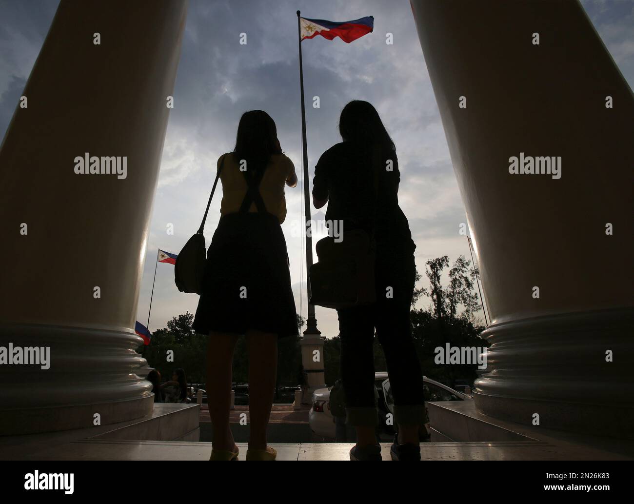 Filipino students stand in front of a Philippine flag outside the ...