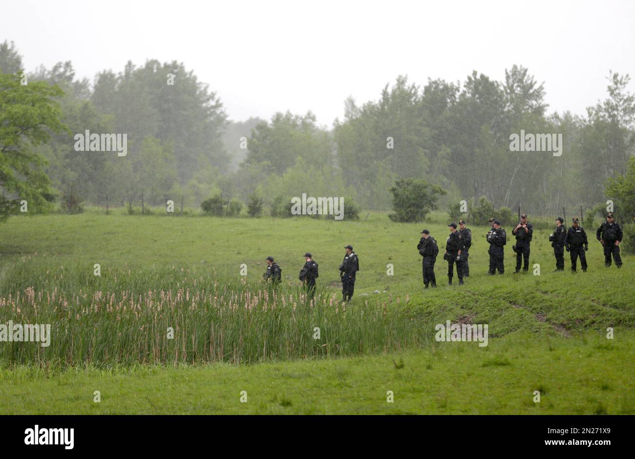 Law enforcement officers walk through a field searching for escaped ...