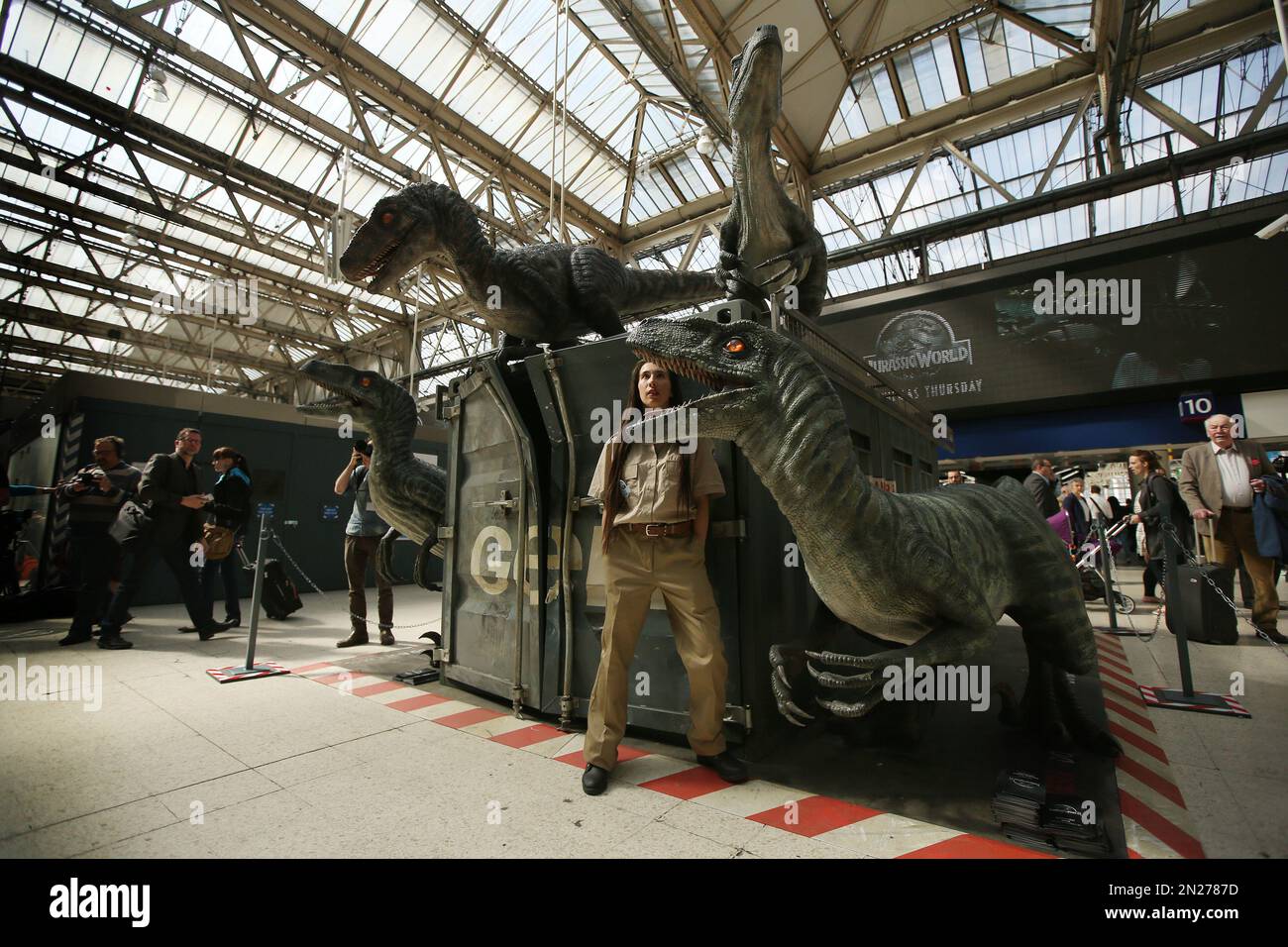 Commuters walk past the model Raptors as part of the Jurassic World ...