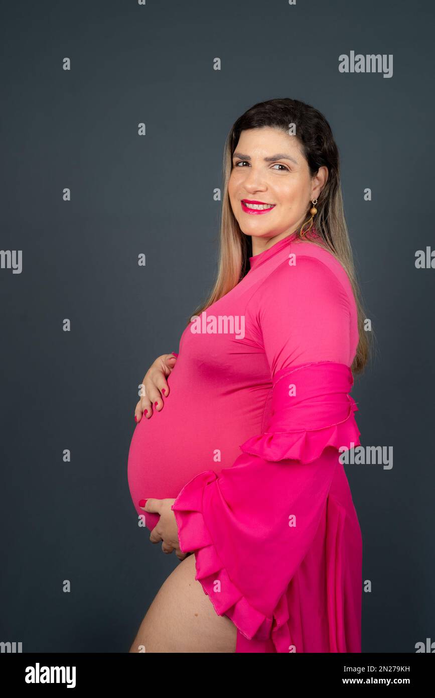 Pregnant woman in profile with hands on belly wearing pink outfit ...