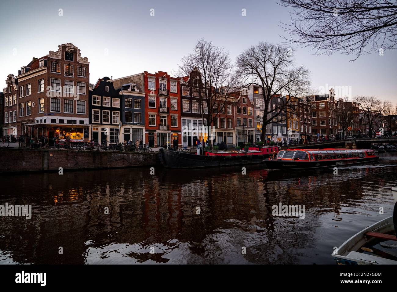 Tour boat in amsterdam canal beneath historic buildings hi-res stock ...