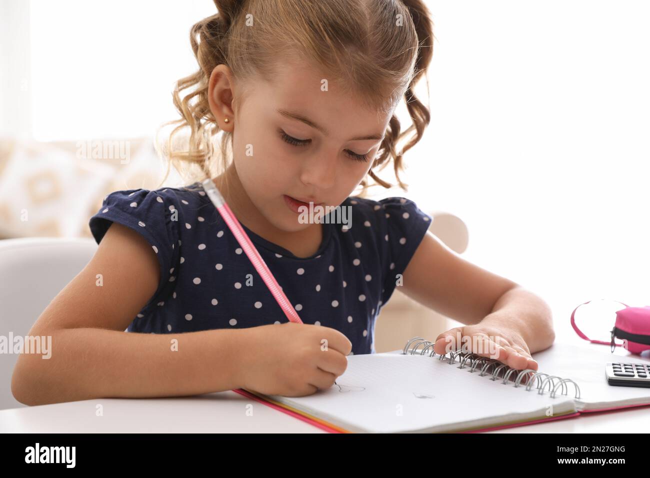 Cute little girl doing homework at table Stock Photo - Alamy