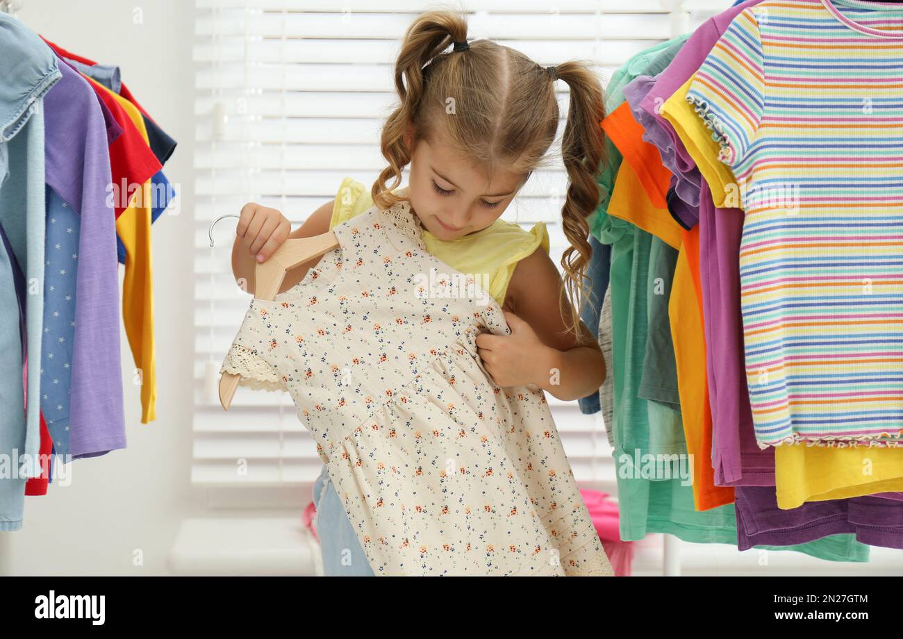 Little girl choosing clothes on racks indoors Stock Photo - Alamy