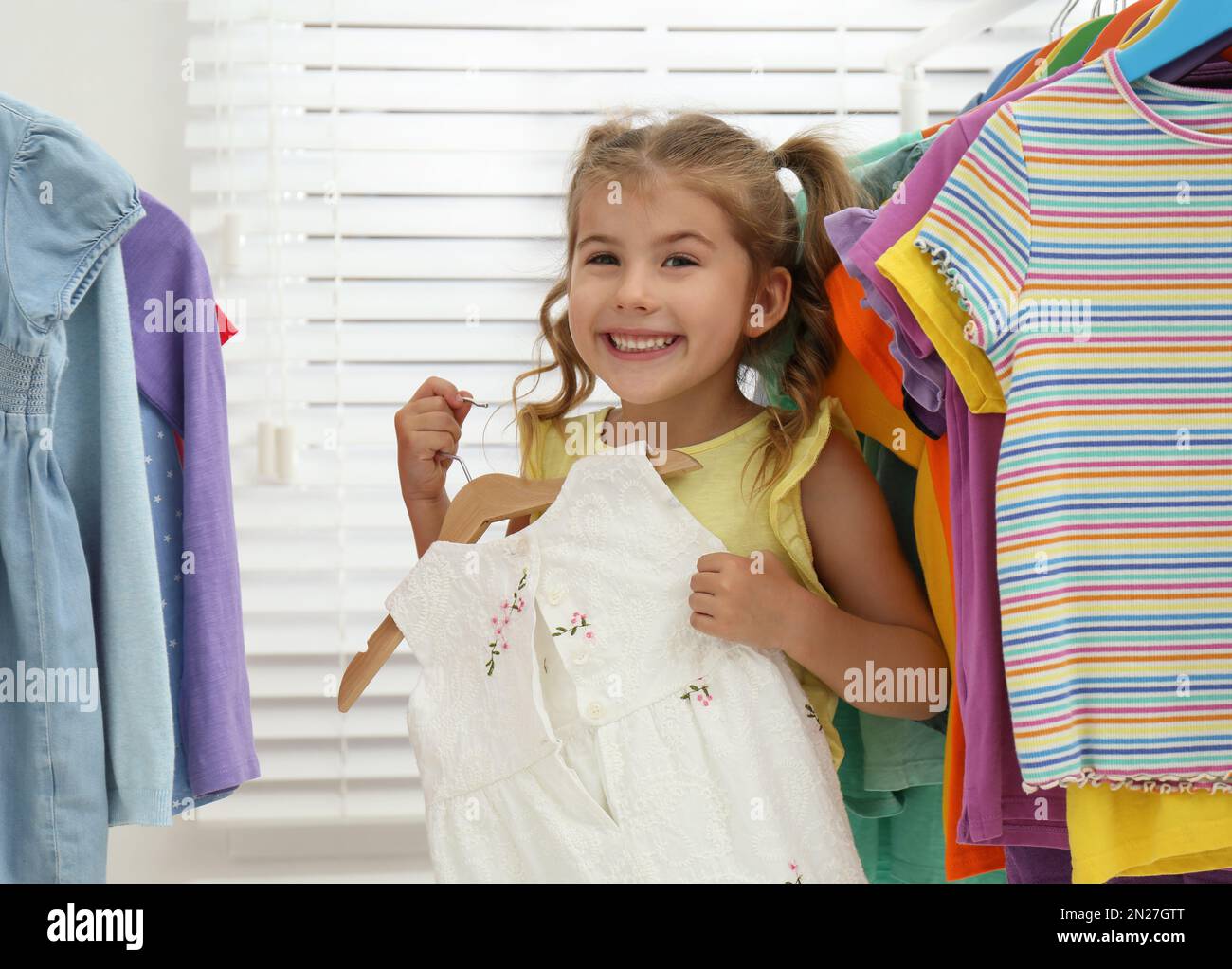 Little girl choosing clothes on rack indoors Stock Photo - Alamy