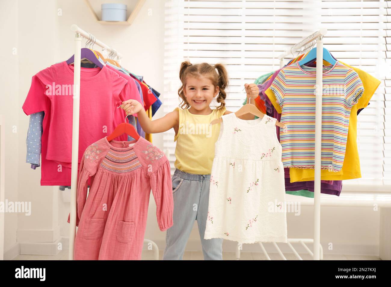 Little girl choosing clothes on racks indoors Stock Photo - Alamy