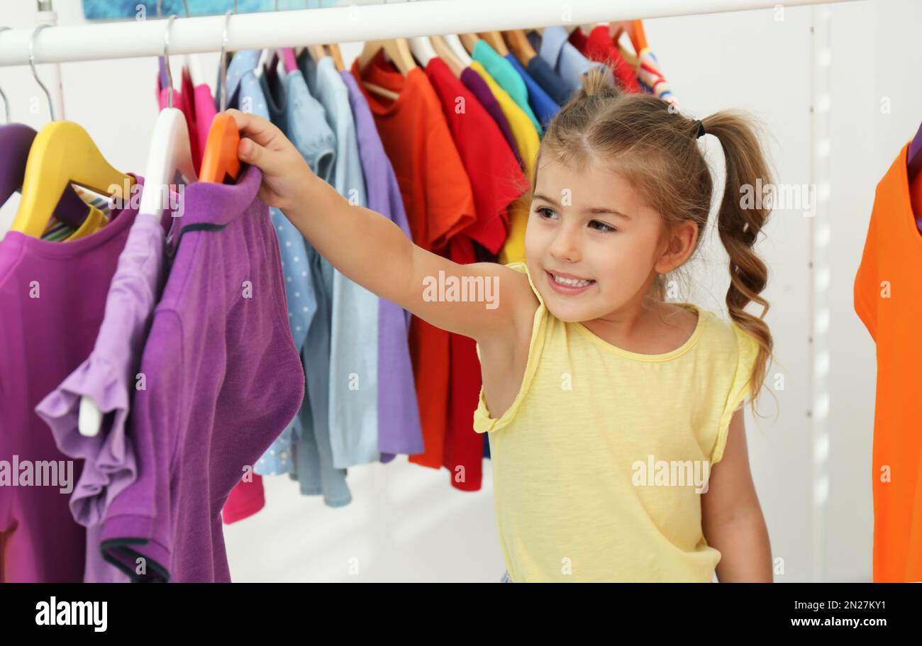 Little girl choosing clothes on rack indoors Stock Photo - Alamy