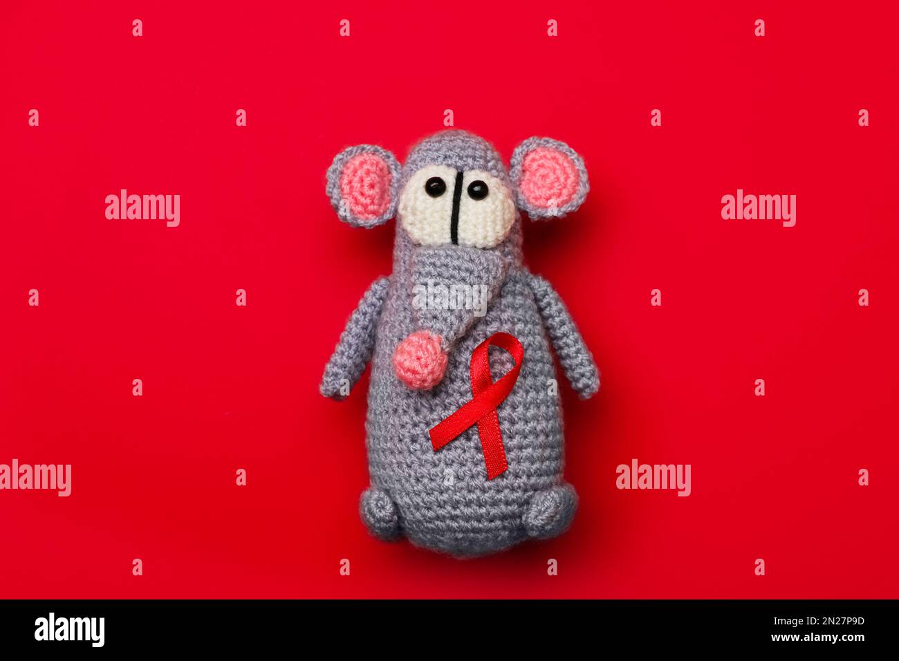 Cute knitted toy mouse with ribbon on red background, top view. AIDS ...