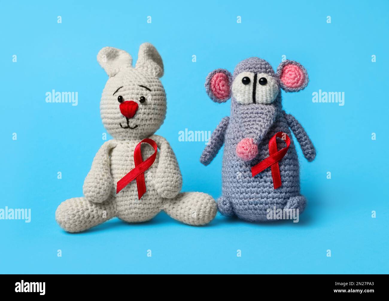 Cute knitted toys with red ribbons on blue background. AIDS disease ...