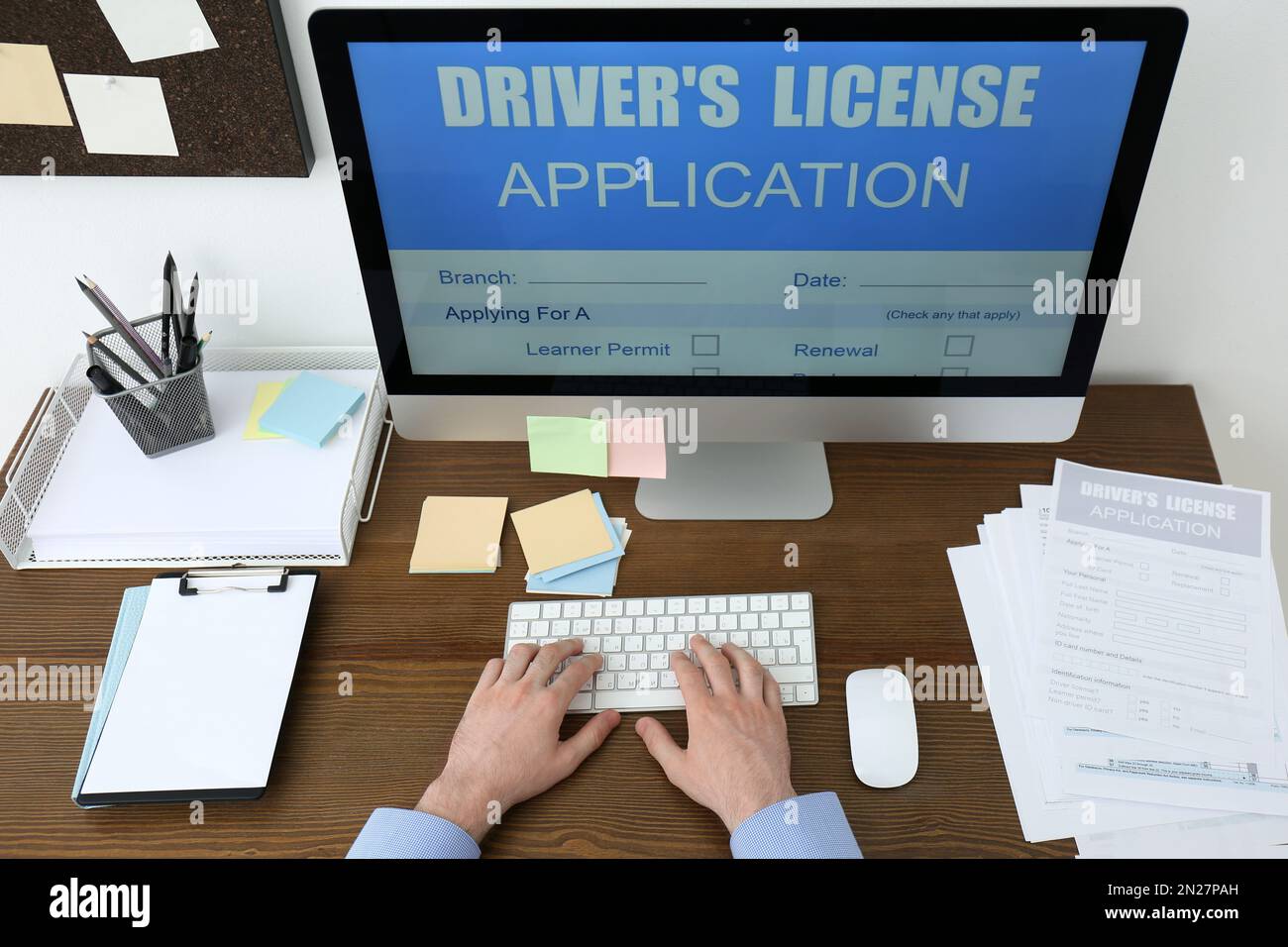 Man using computer to fill driver's license application form at table in office, closeup Stock ...