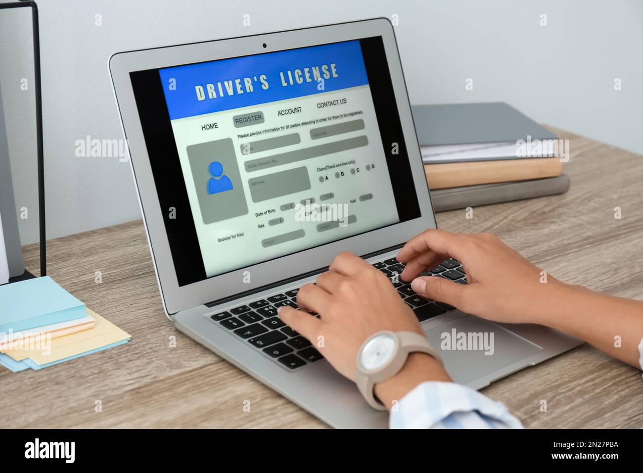 Woman using laptop to fill driver's license application form at table in office, closeup Stock ...