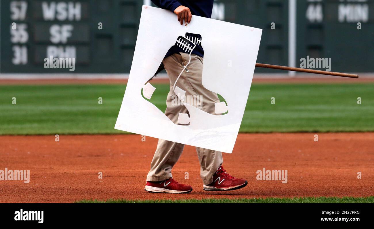 A Boston Red Sox ground crew worker carries a stencil towards the ...