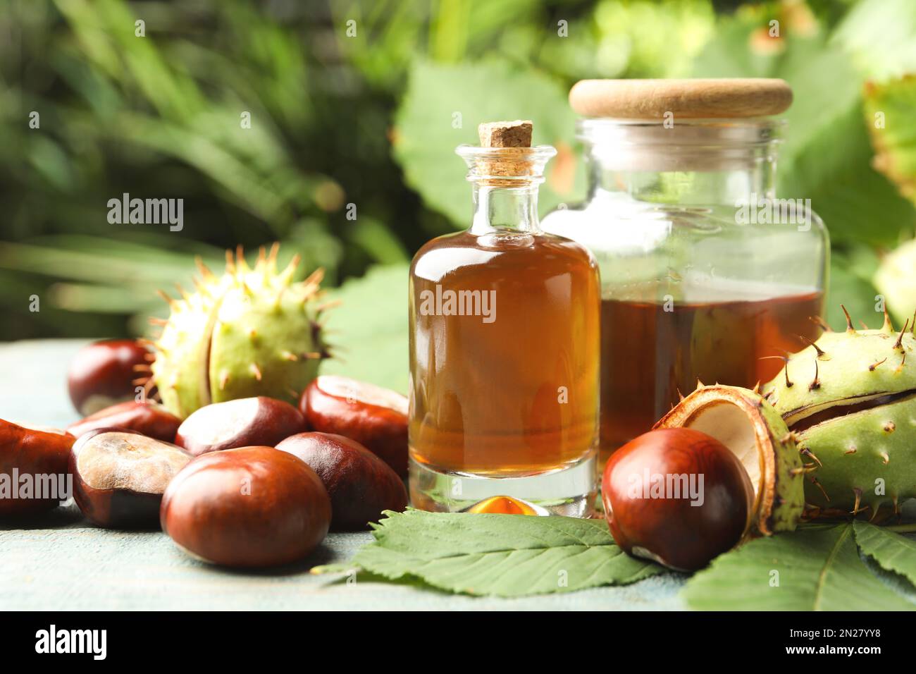 Chestnuts and essential oil on table against blurred background Stock ...