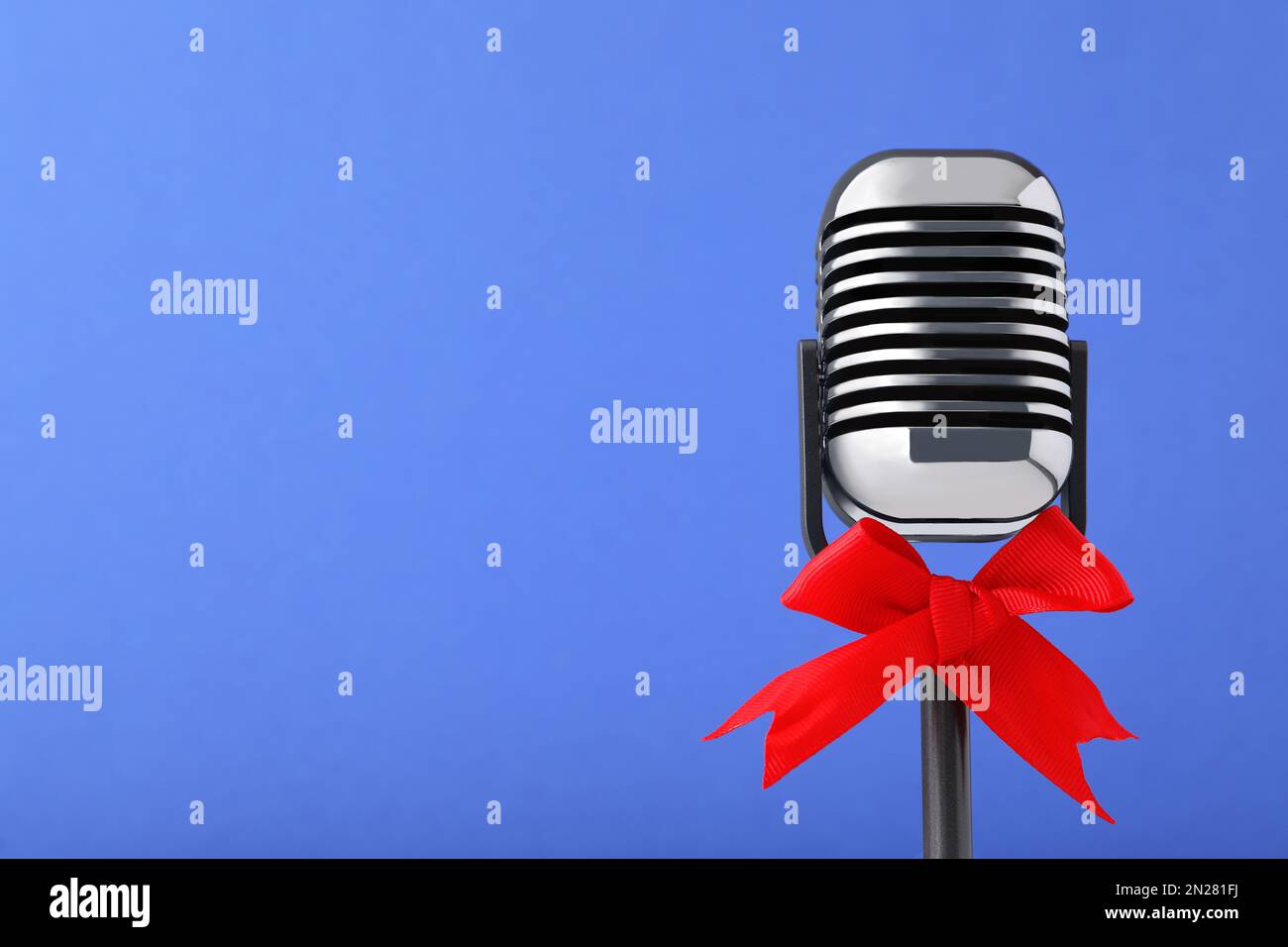 Retro microphone with red bow on blue background, space for text ...