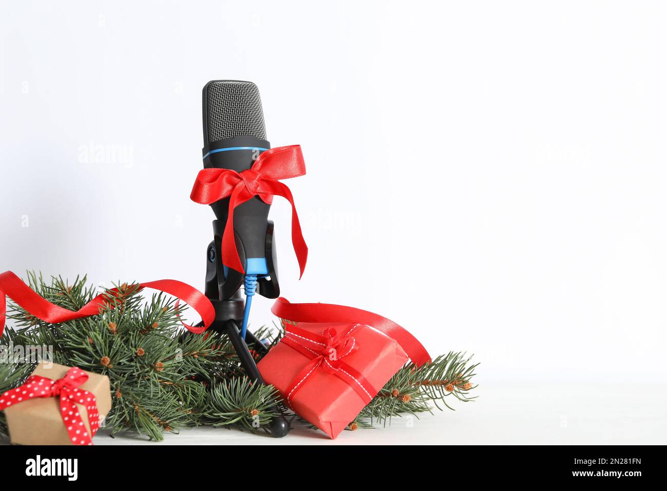 Microphone with gift boxes and festive decor on white background, space ...