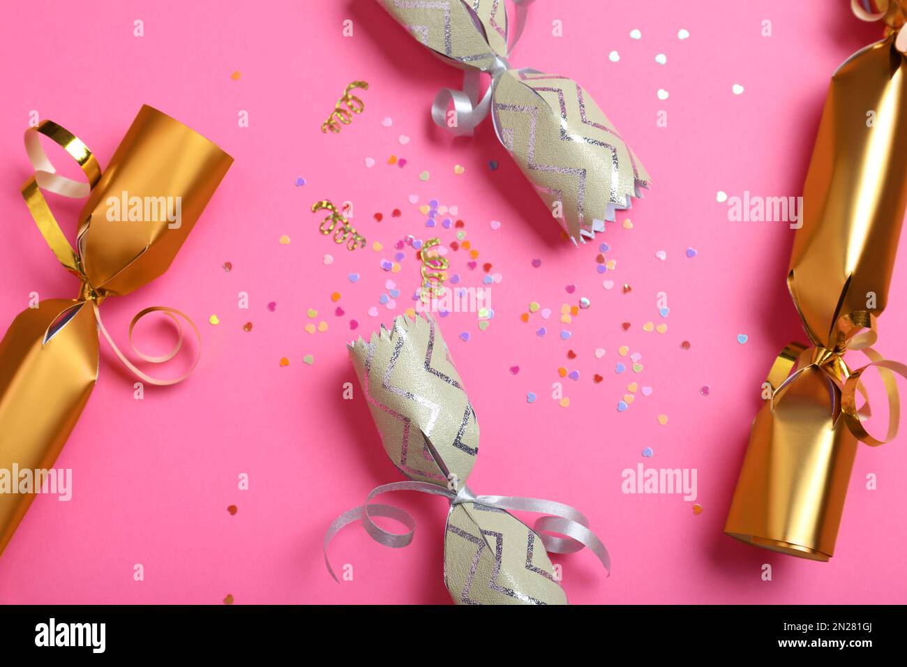 Open and closed Christmas crackers with shiny confetti on pink ...