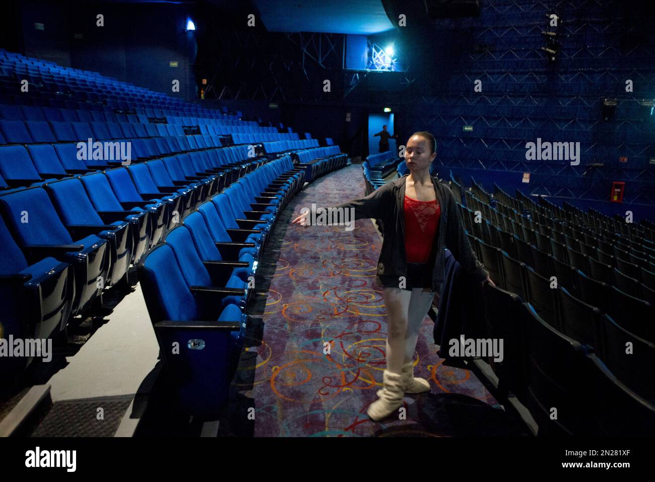 A ballerina uses theater seats for a barre as she warms up ahead of a ...
