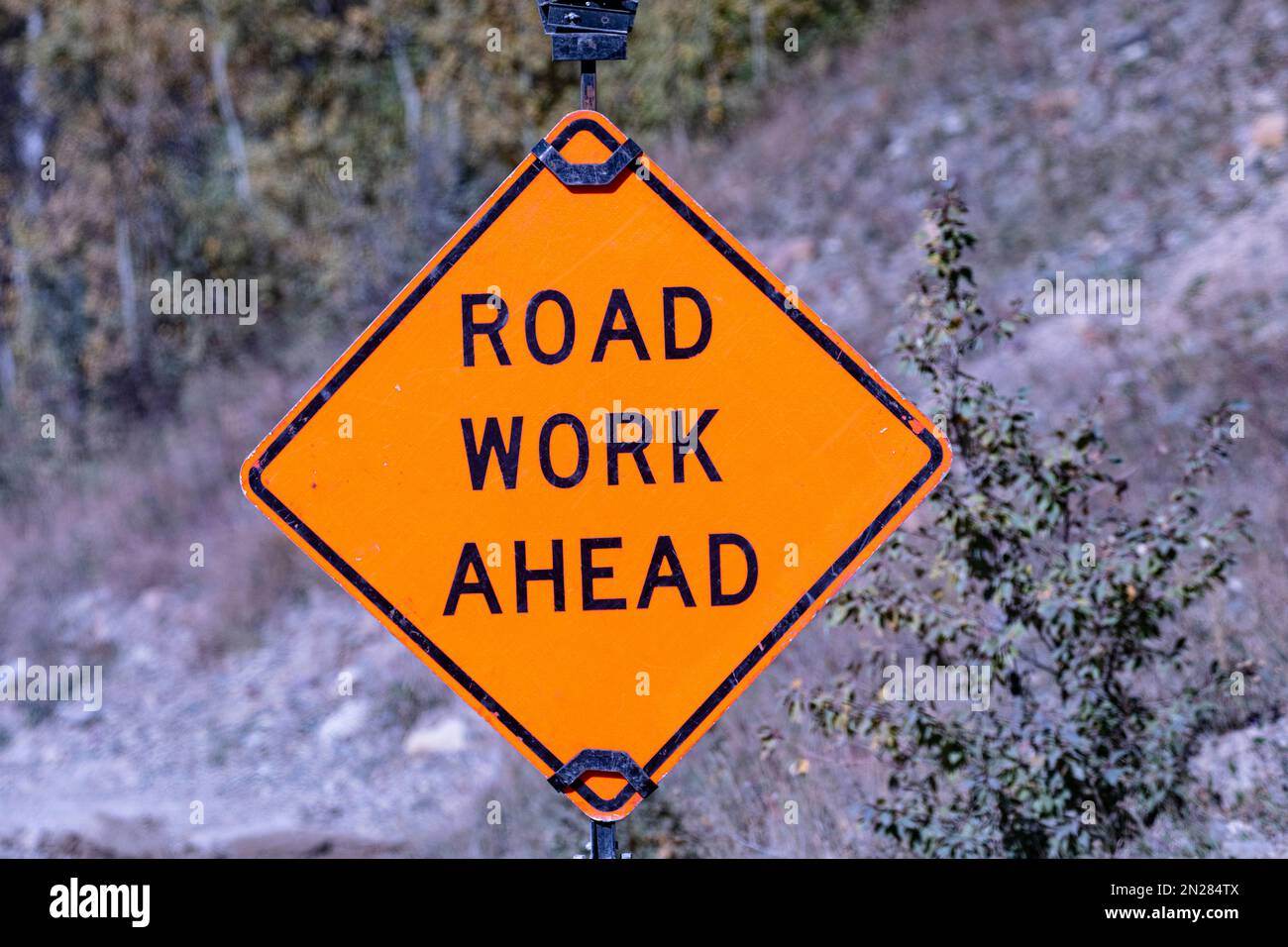 Battered, but clearly legible, road safety sign warns ROAD WORK AHEAD ...