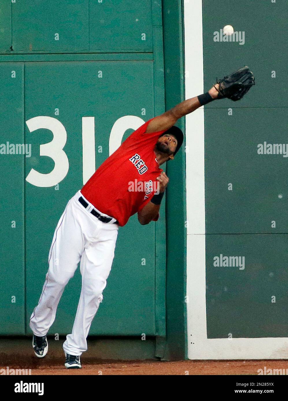 Boston Red Sox left fielder Carlos Peguero leans over to catch a fly ...