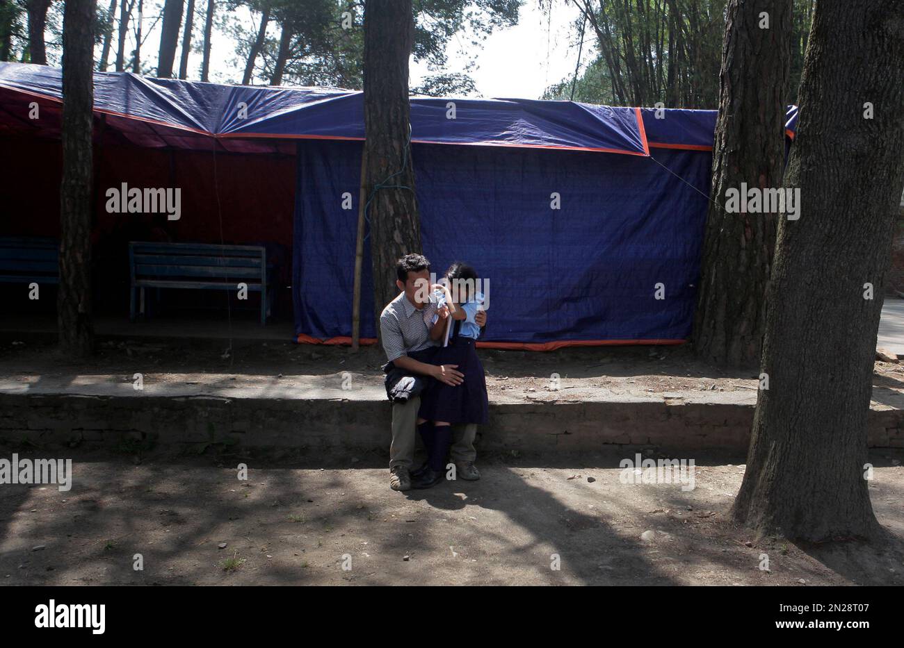 A Nepalese man comforts his crying daughter at her school premise, as ...