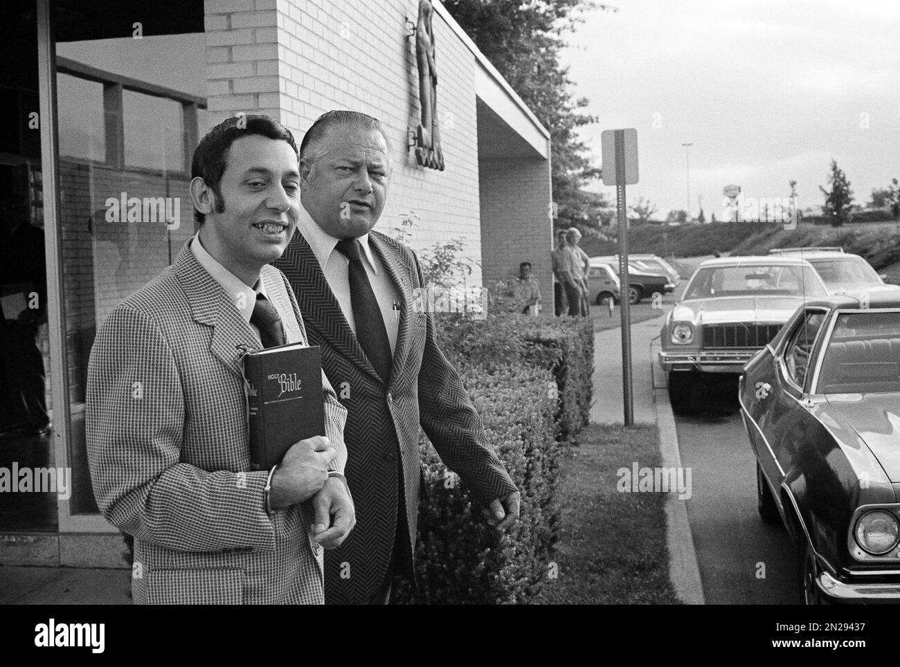 Joseph Kallinger, left, of Philadelphia, his handcuffed wrists carrying ...