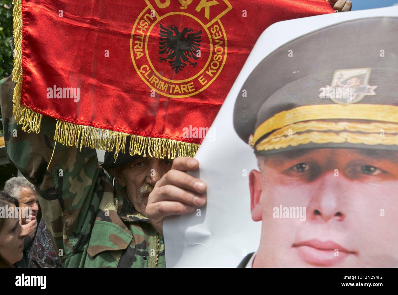 An ethnic Albanian holds the flag of the former Kosovo Liberation Army ...