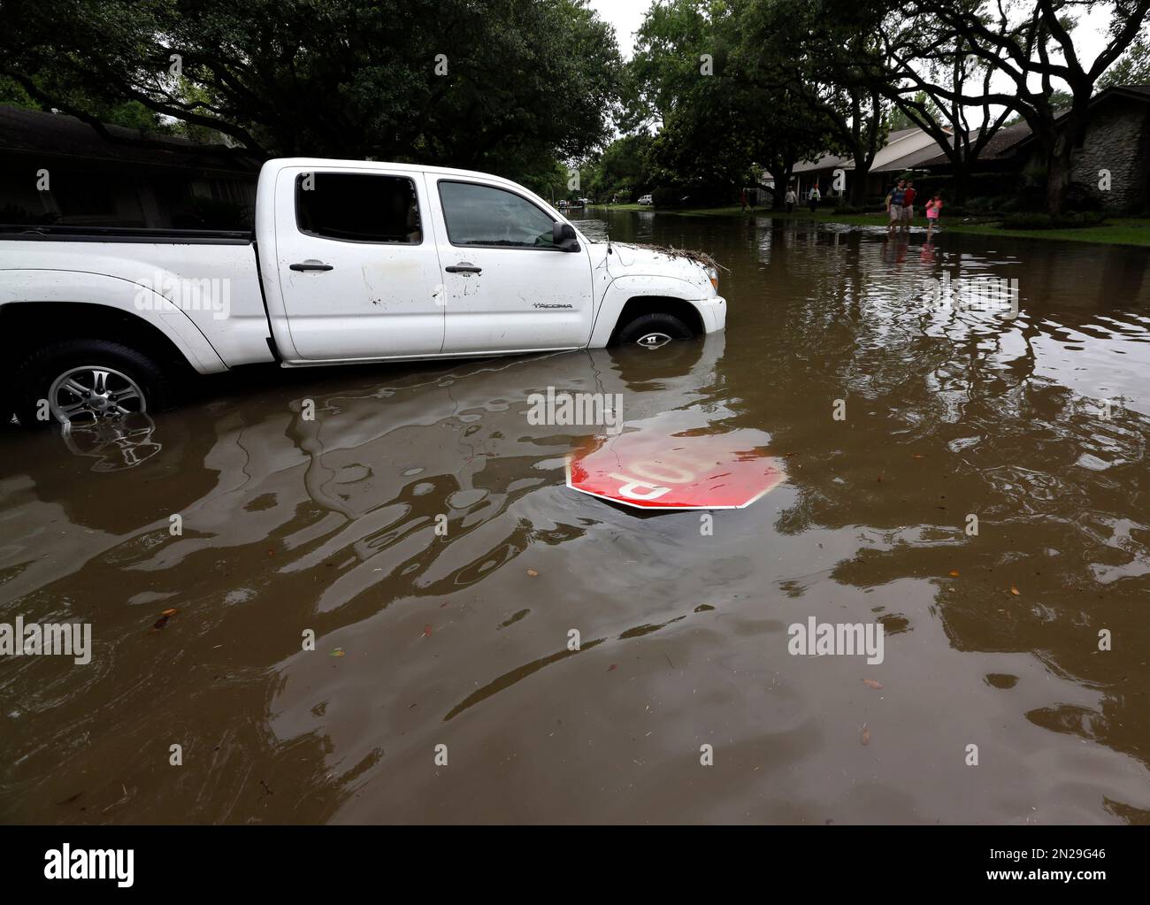 Residents walk past a flooded truck in their neighborhood in Houston ...