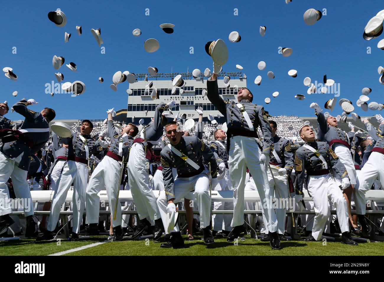 Graduating cadets toss their hats at the end of a graduation and ...