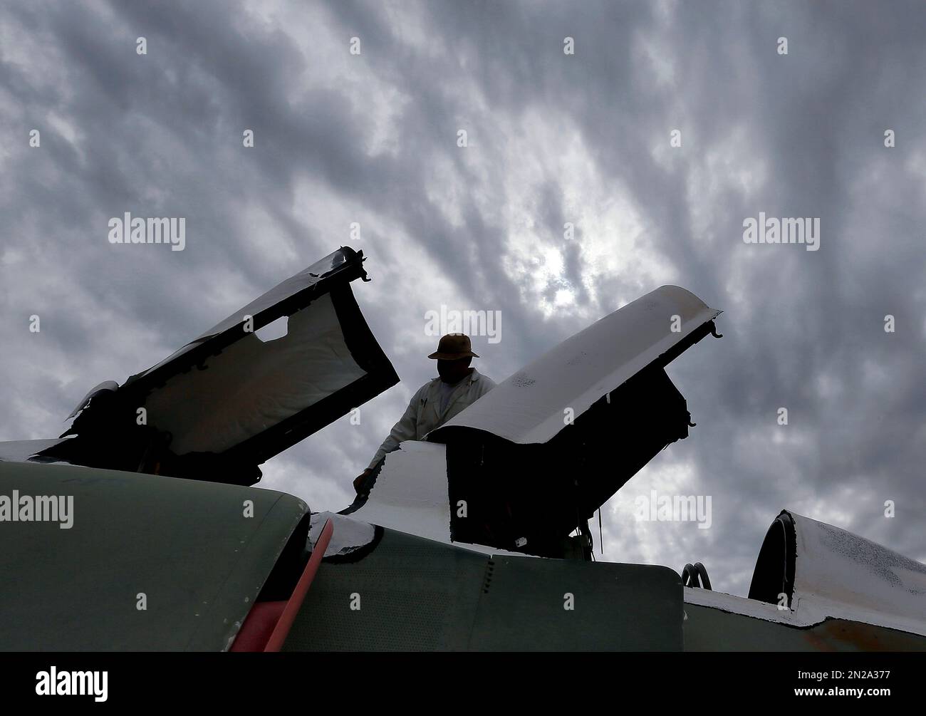 A demilitarization crew member removes components from the cockpit of ...