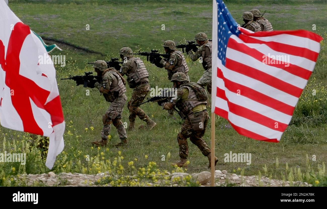 US and Georgian servicemen, with Georgian and US flags in front, take ...