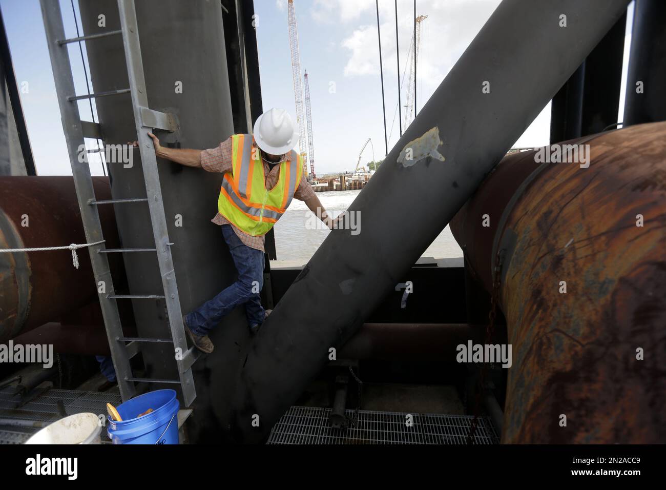 A worker climbs on pipes for pumping water at the 17th Street Canal ...