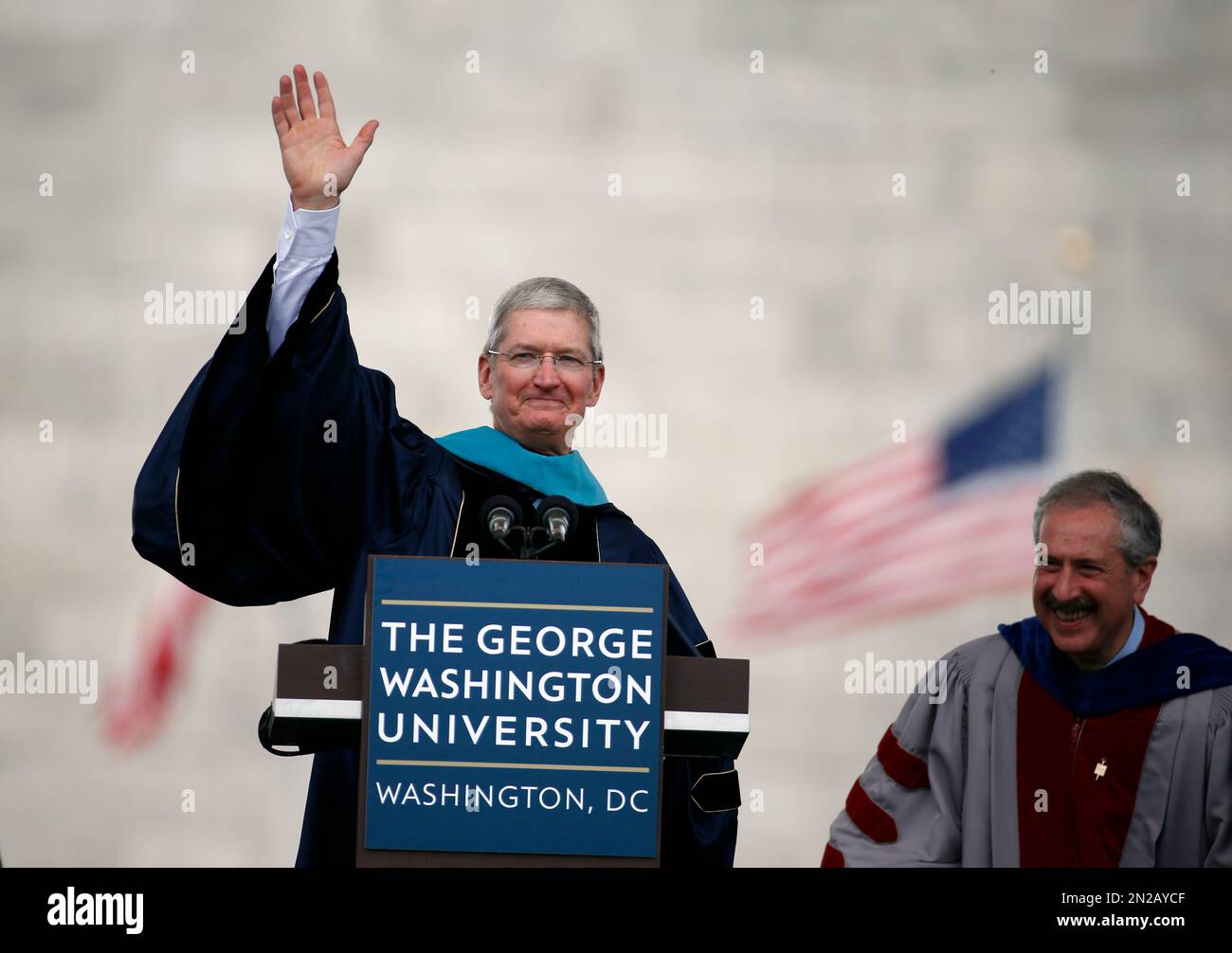 Apple CEO Tim Cook, left, waves after speaking, as university provost ...