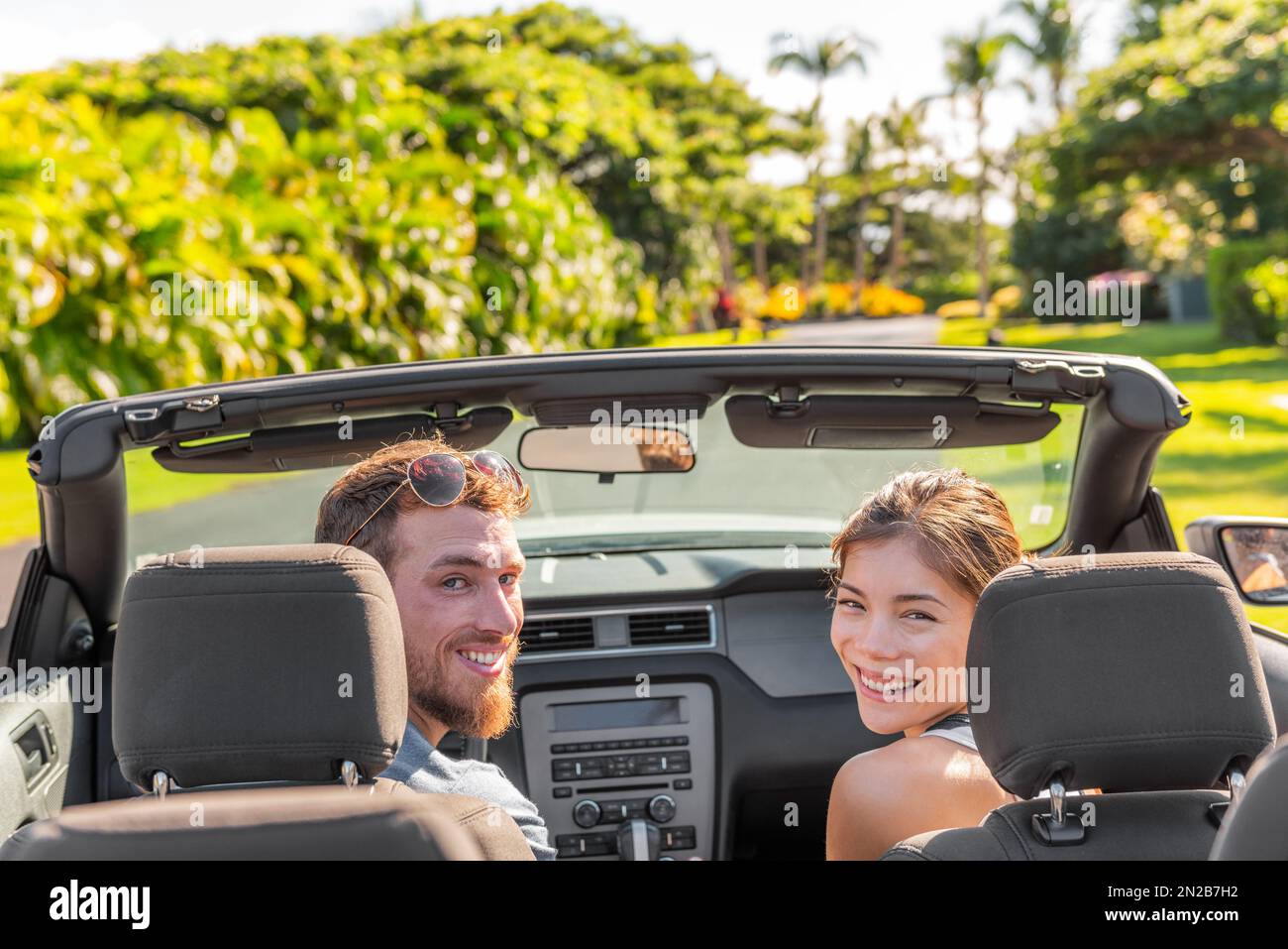Happy road trip couple having fun driving luxury sports convertible car ...